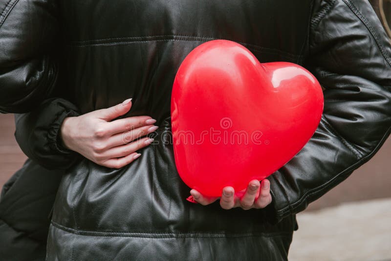 The Guy Holds a Red Heart Ball in His Hand Behind His Back Stock Photo ...