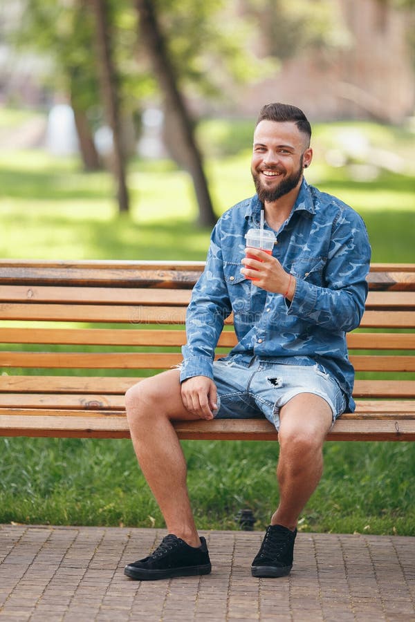 A Guy with Lemonade is Resting in a Park on a Bench in the Spring ...