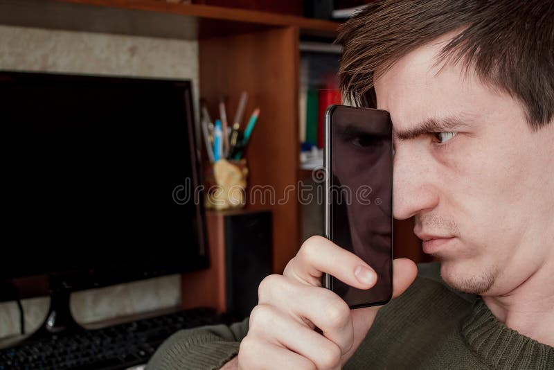 Guy Looks at the Screen of a Black Smartphone, through the Reflection ...