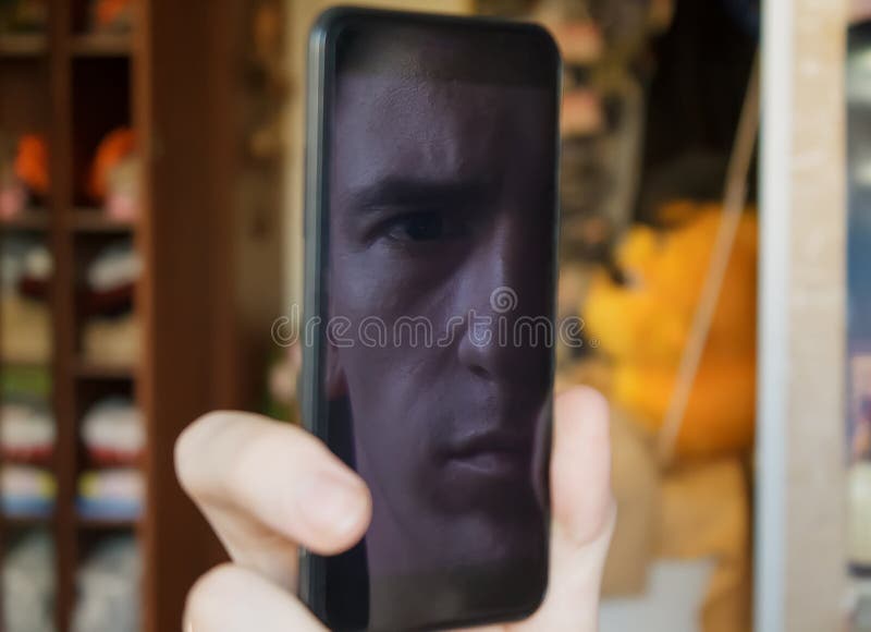 Guy Looks at the Screen of a Black Smartphone, through the Reflection ...