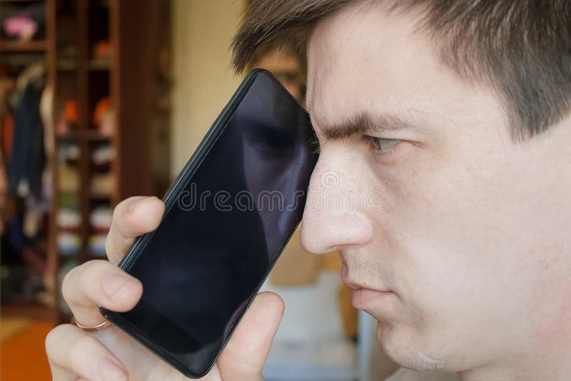 Guy Looks at the Screen of a Black Smartphone, through the Reflection ...