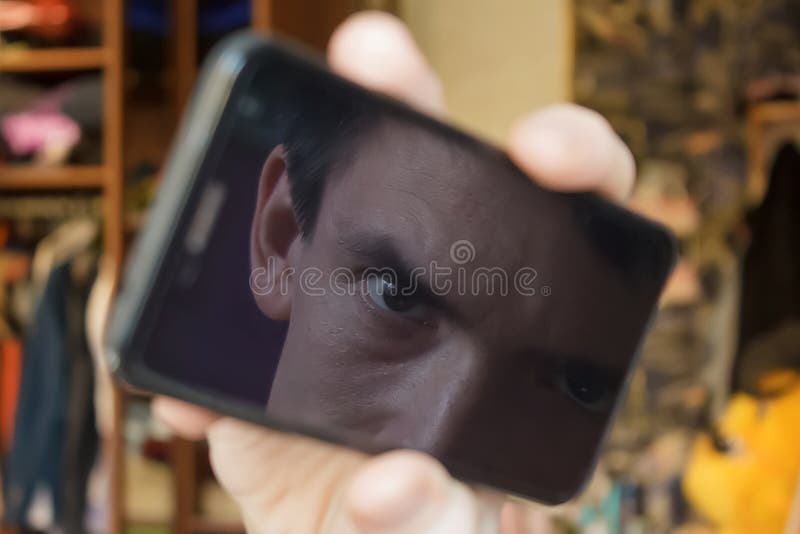 Guy Looks at the Screen of a Black Smartphone, through the Reflection ...