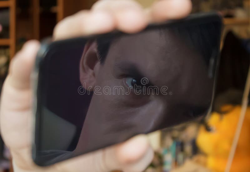 Guy Looks at the Screen of a Black Smartphone, through the Reflection ...
