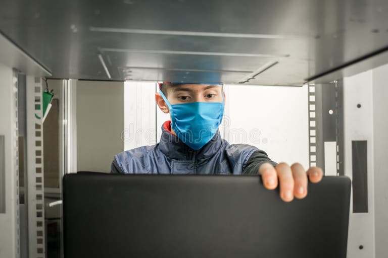A Guy in Medical Mask is Working in Front of a Laptop. Programmer in ...