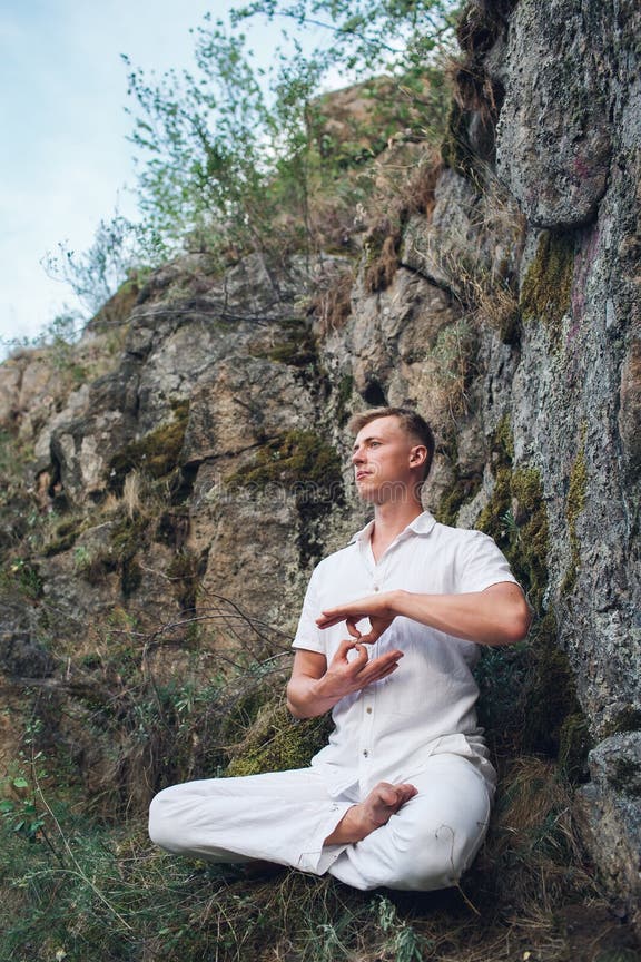 The Guy Meditates in the Lotus Position on the Rock. Stock Photo ...