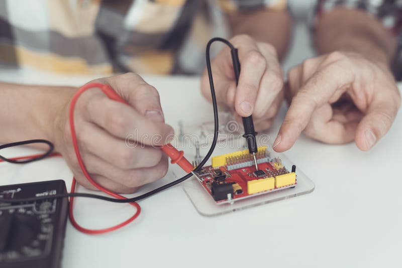 The Guy and the Man Examine the Board Using a Multimeter. they Measure ...