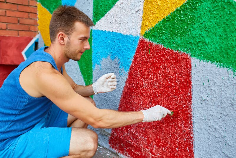 The Guy Paints the Wall with a Brush in Bright Colors Stock Photo ...