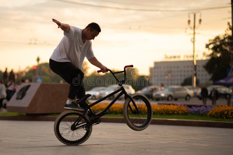 The Guy Performs a Stunt on BMX, Standing on the Rear Wheel Stock Photo ...