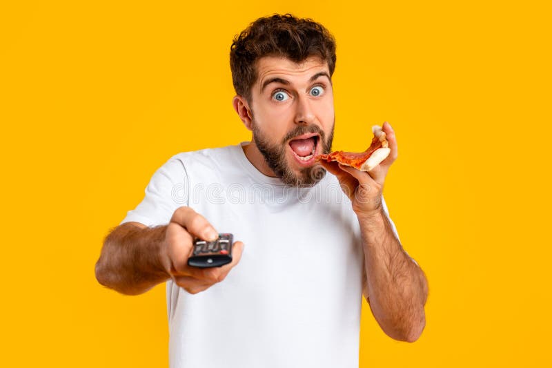 Guy Points Remote Controller Savoring Pizza Slice on Yellow Backdrop ...
