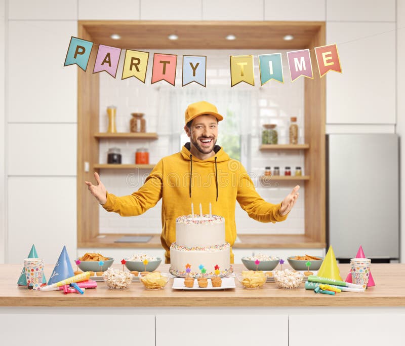 Guy Posing Behind a Counter with Party Snacks and a Cake in a Kitchen ...
