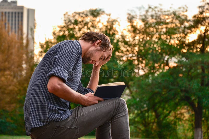 Guy reading book in park stock image. Image of cute, reading - 78740337