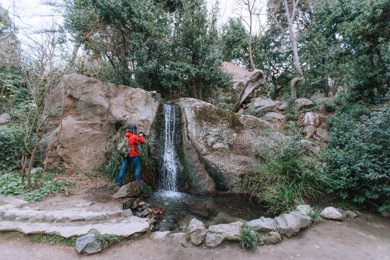 A Guy in a Red Jacket Photographs on a Smartphone a Waterfall . Stock ...