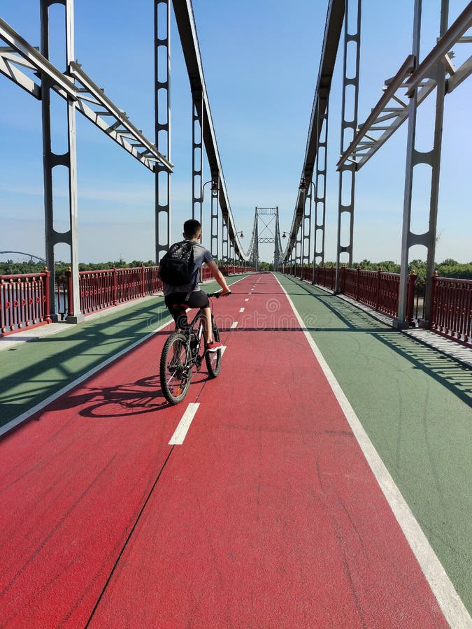 A Guy Rides a Bicycle with a Backpack on a Path on a Bridge in ...