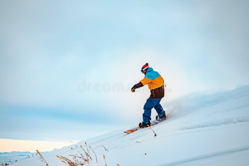 The Guy is Riding a Snowboard. in the Mountains in Pristine Snow Stock ...