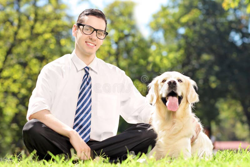 Guy Sitting on a Green Grass Next To His Dog in Park Stock Photo ...