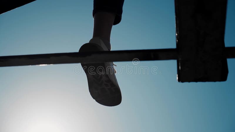 The Guy is Sitting with His Legs Dangling on the Edge of the Bridge at ...