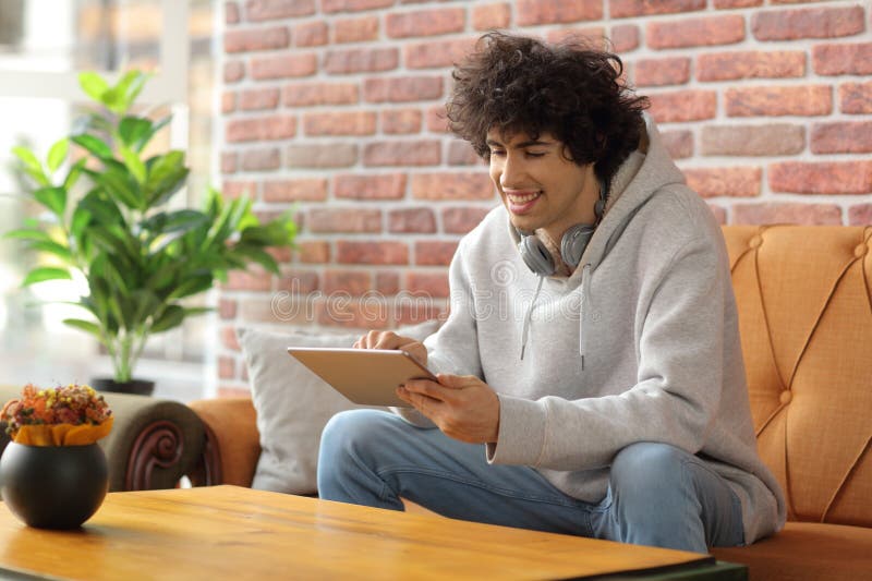 Guy Sitting on a Sofa in a Cafe and Using a Tablet Stock Photo - Image ...