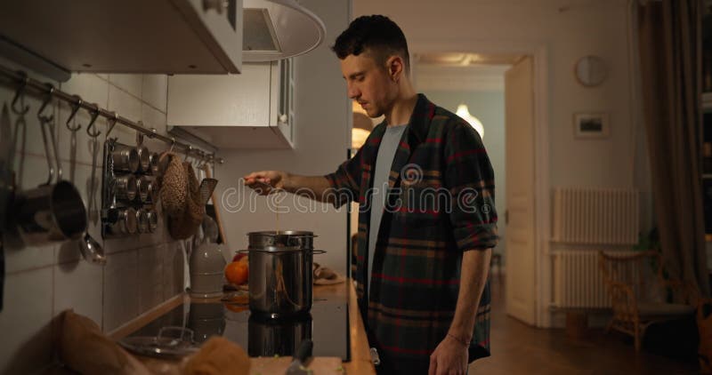 Guy Stirs Spaghetti and Tests it for Doneness while Preparing Dinner in ...