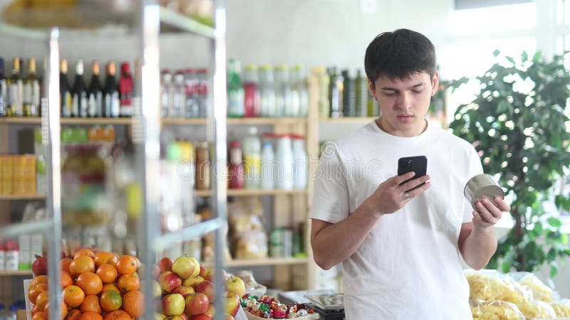 Young Man Customer at Shop Scans QR Code on Tin Cans of Preserves Using ...