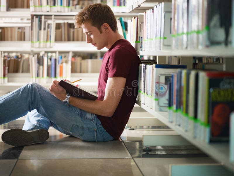 Young Man Doing Homework and Studying in College Library Stock Photo ...