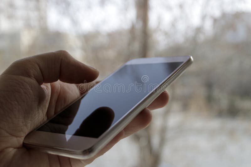 The Guy at the Window Holds a Smartphone in His Hand. the Man Uses the ...