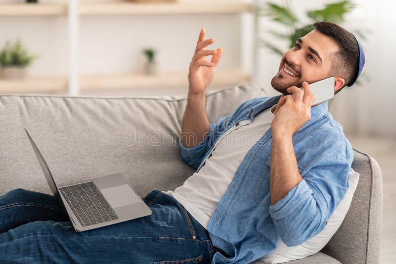 Guy Working on Computer and Talking on Cellphone at Home Stock Image ...