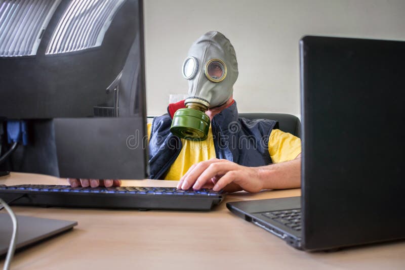The Guy Works at a Computer in Quarantine. a Man in a Gas Mask Sits at ...