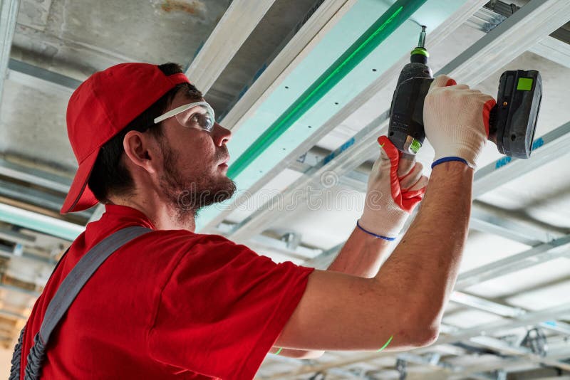 Installation of Drywall. Workers are Using Screws and a Screwdriver To ...
