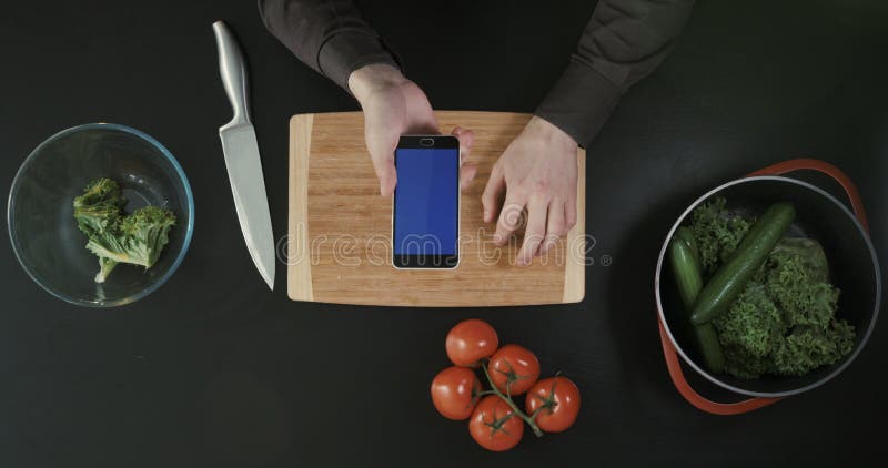 Haands Scrollaing the Phone Screen. Kitchen Table with Food, Knife and ...