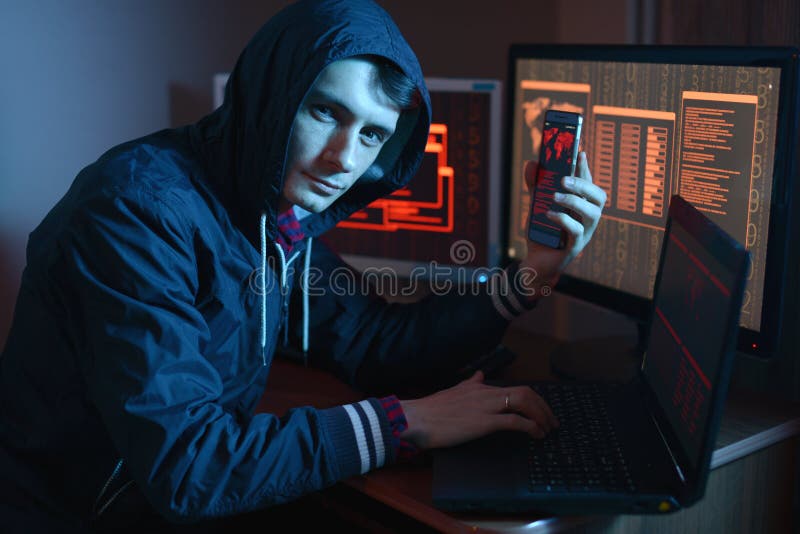 Hacker in the Hood Holding the Phone in His Hands Trying To Hack the ...