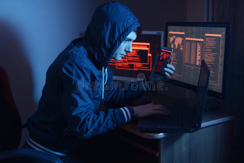 Hacker in the Hood Holding the Phone in His Hands Trying To Hack the ...