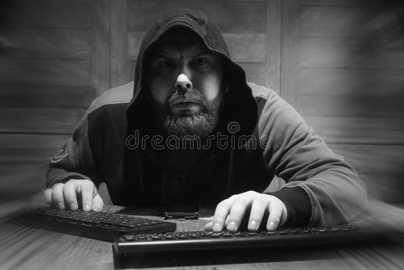 The Hacker in the Hood Sits and Works Behind the Computer Stock Photo ...