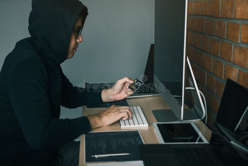 Hacker in the Hood Working with Computer and Holding Credit Card with ...