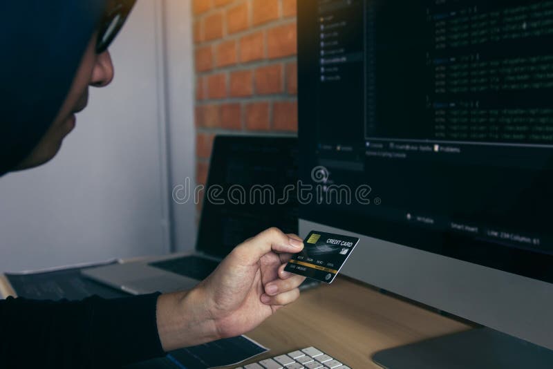 Hacker in the Hood Working with Computer and Holding Credit Card with ...