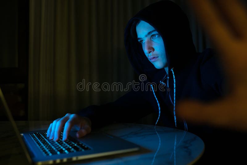 Hacker with a Laptop Hiding His Face by Hand. Hacker is Hacking into ...