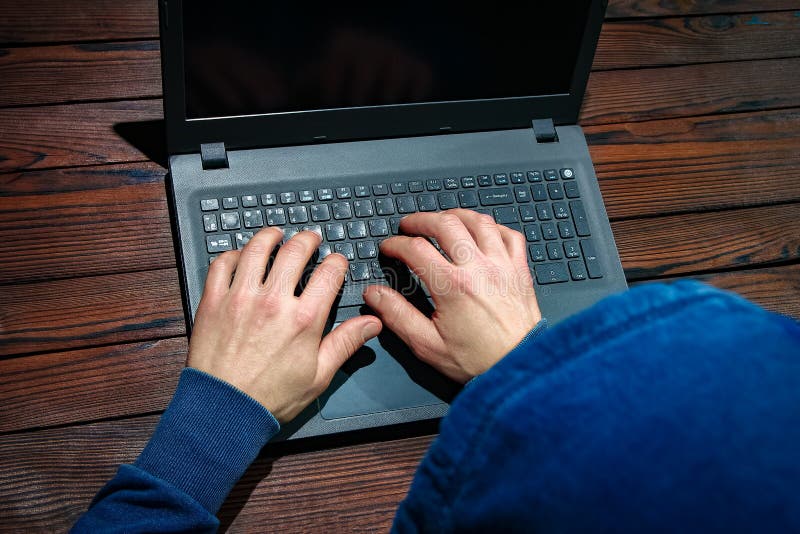 A Hacker with Laptop Sits at a Table and Abstract Binary Code. Business ...