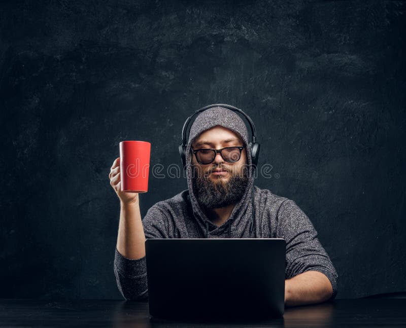 A Hacker Sits Behind a Laptop in a Dark Office and Stares Intently at ...