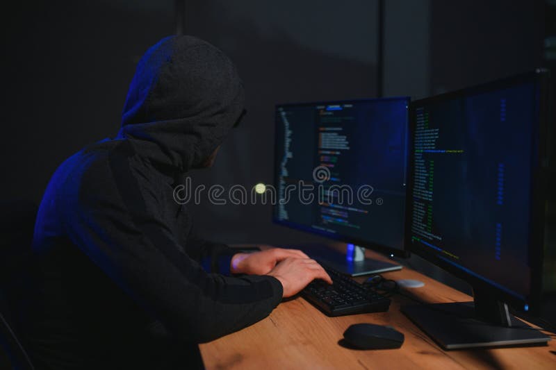 A Hacker Sitting at His Desk in the Dark with Several Monitors, on ...
