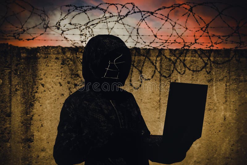A Hacker Stands Against the Wall of a Prison with Barbed Wire ...