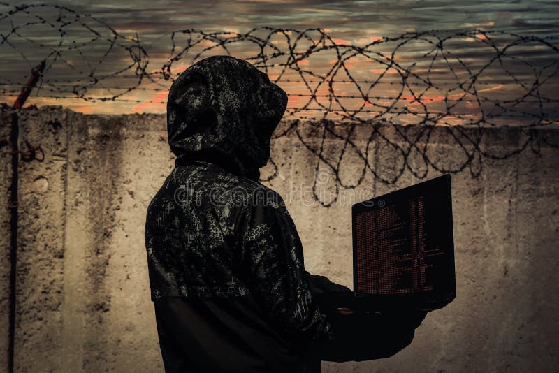 A Hacker Stands Against the Wall of a Prison with Barbed Wire ...