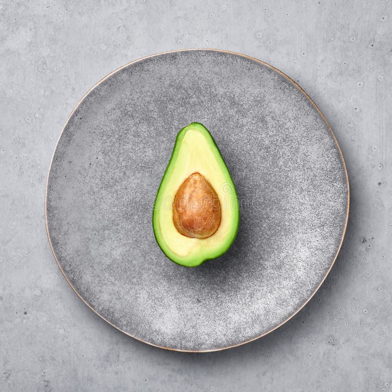 Half Avocado in Gray Hand Made Matte Plate on Concrete Rough Backdrop ...