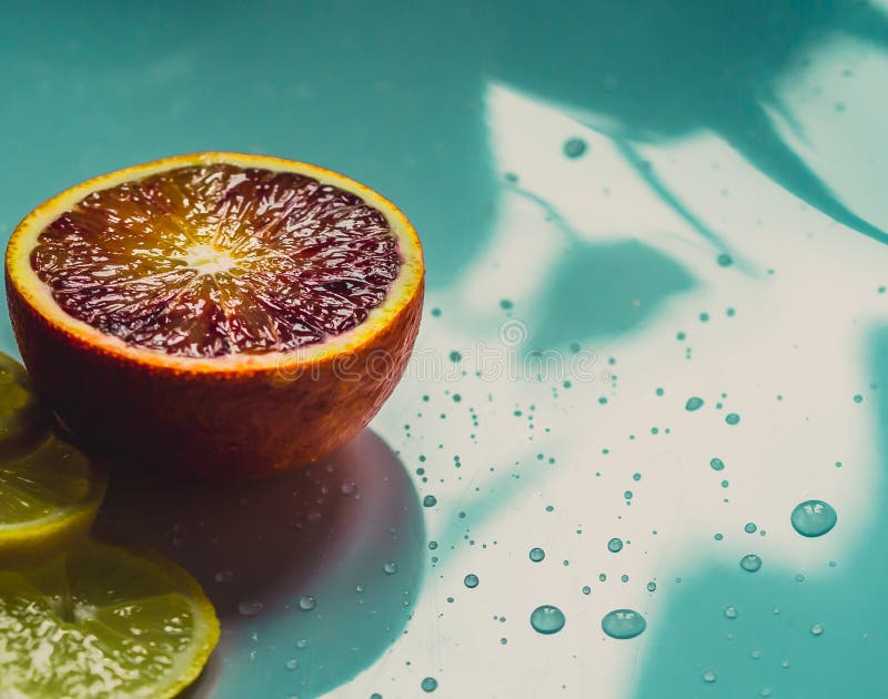 Half a Blood Orange with Lemon Slices and Water Drops in the Background ...