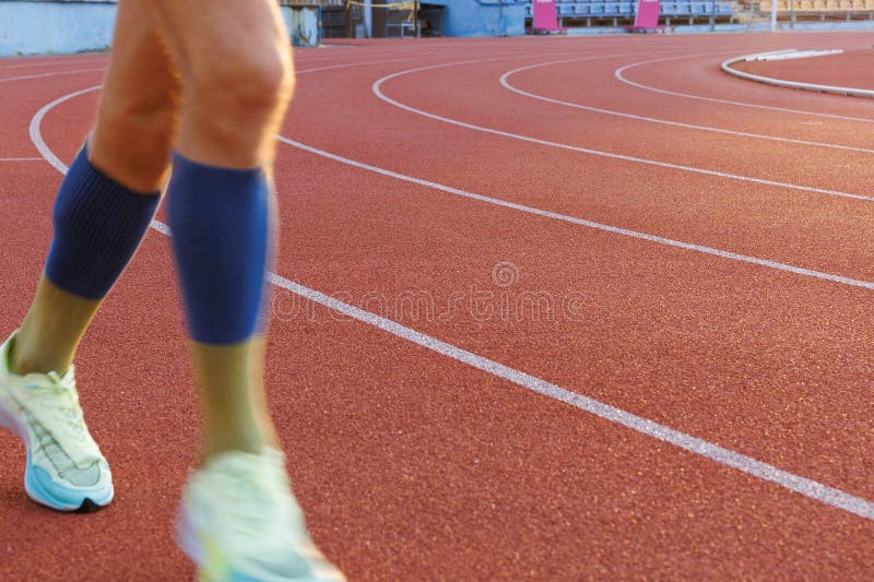 Half-blurred Legs of a Runner in Motion on a Running Track Around the ...