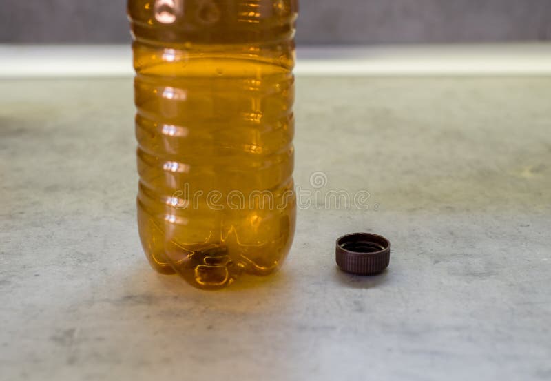 Half Brown Transparent Plastic Bottle Rests on Countertop. Cap Sits ...