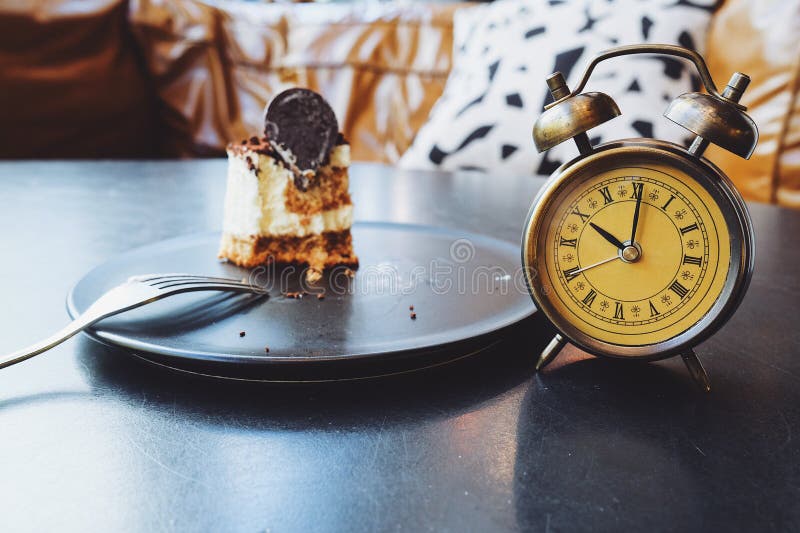 Half Chocolate Cake and Alarm Clock on Black Table Stock Photo - Image ...