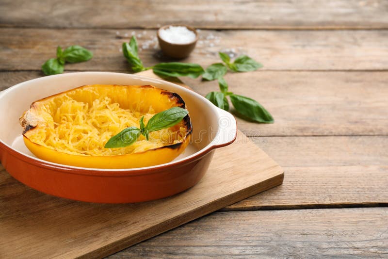 Half of Cooked Spaghetti Squash with Basil in Baking Dish on Wooden ...