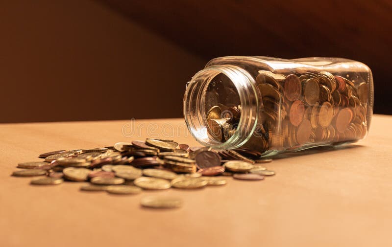 Half Empty Money Jar with Coins Over the Table. Save Money Concept ...