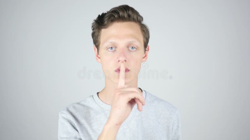 Halten Sie Die Ruhe Und Secert Lokalisierte Geste Durch Jungen Mann