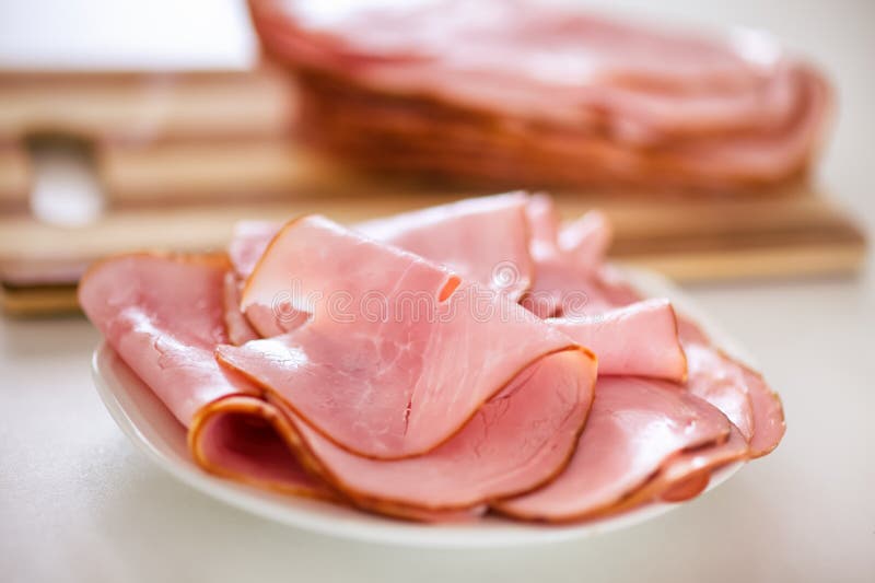 Ham Slices on White Plate with a Chopping Board with a Stack of Ham in ...