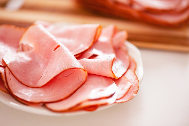 Ham Slices on a White Plate and a Chopping Board with a Stack of Ham on ...